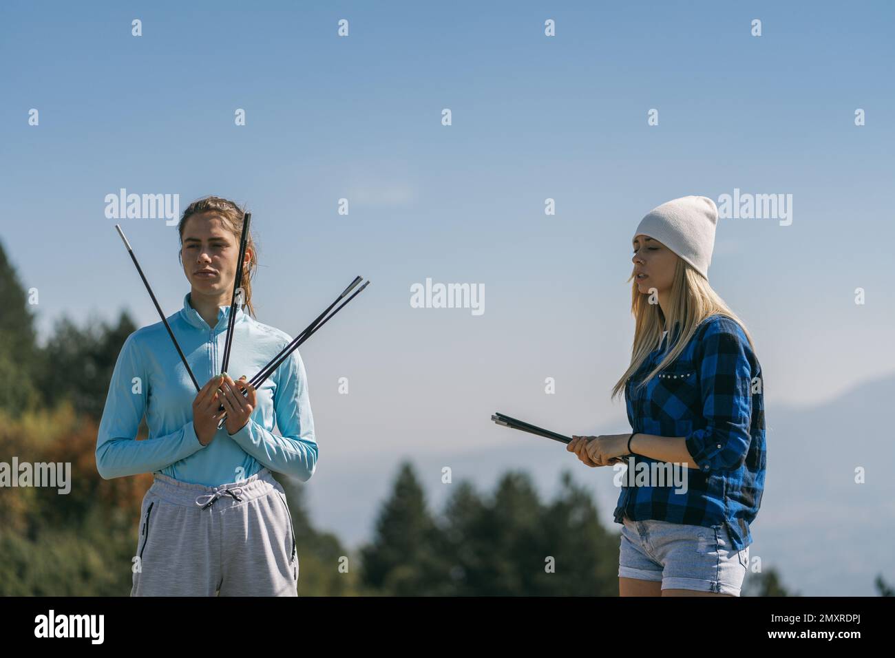 Two beautiful girls holding sticks from the tent while standing at the ...