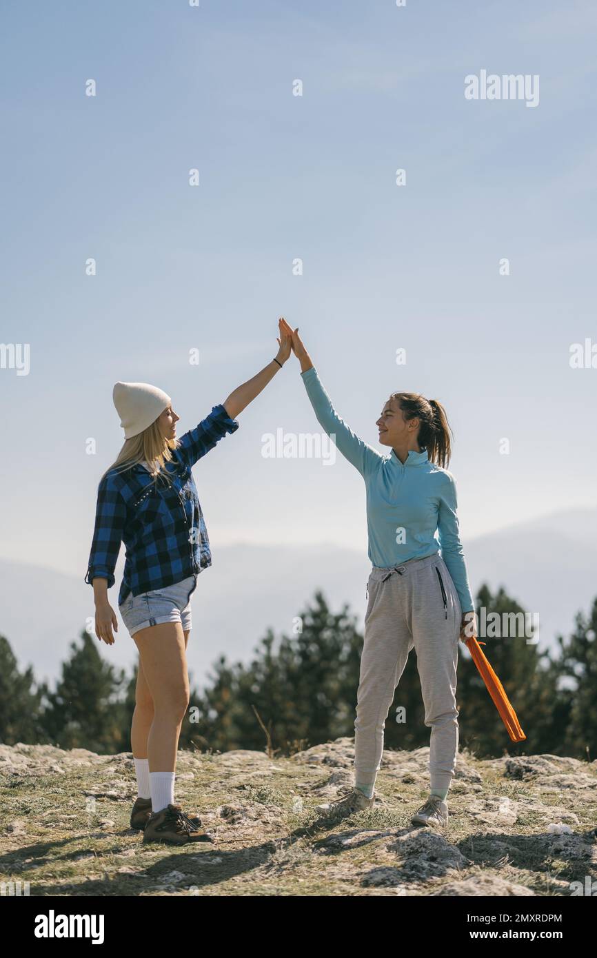 Two pretty girls high fiving while standing at the mountain Stock Photo ...