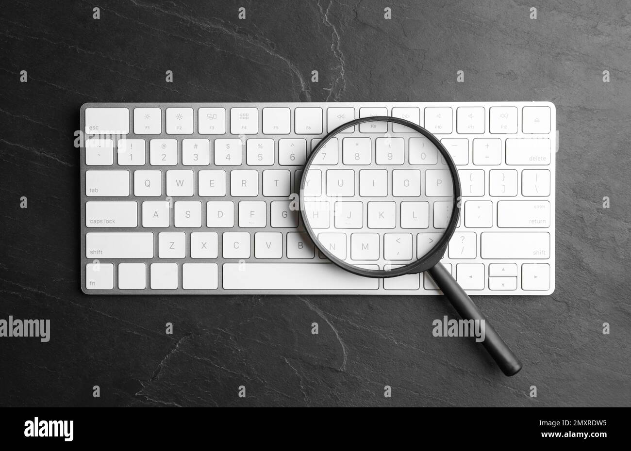 Magnifier glass and keyboard on black slate background, flat lay. Find ...