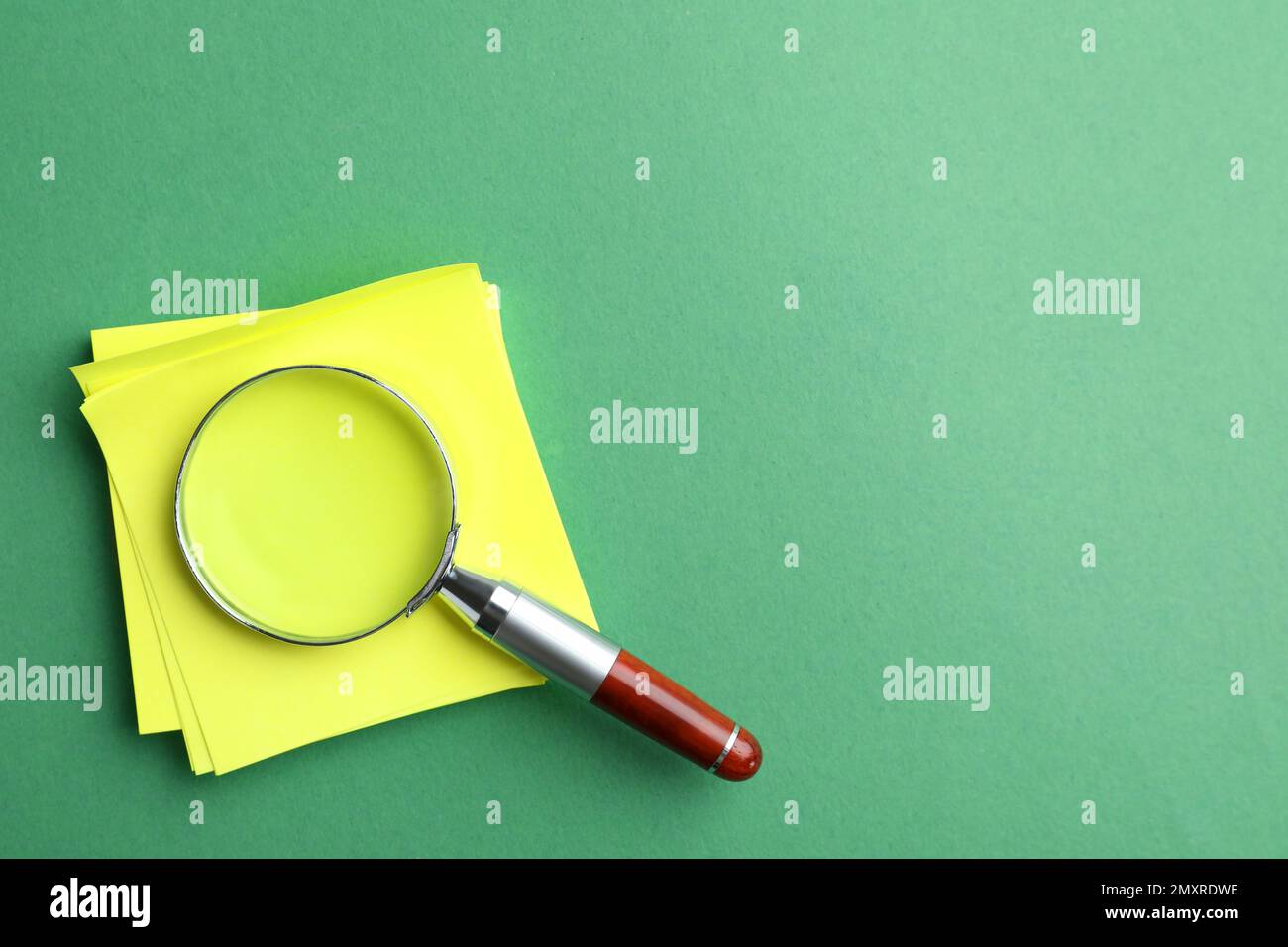 Magnifier glass and empty paper sheets on green background, flat lay ...