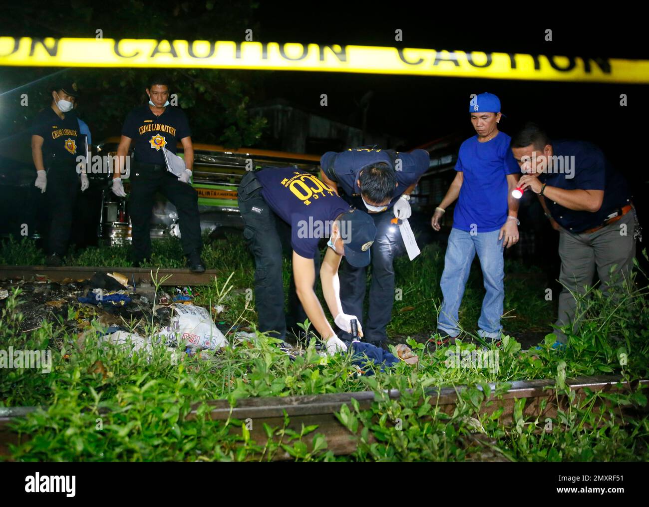 Police investigators examine the body of one of the suspects killed in ...