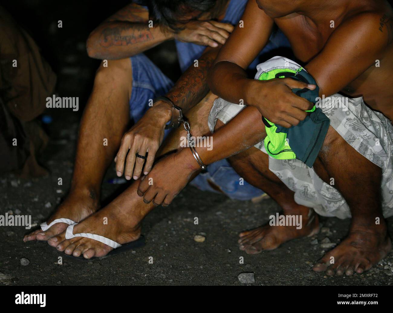 Suspected drug pushers are handcuffed following their arrest in an ...