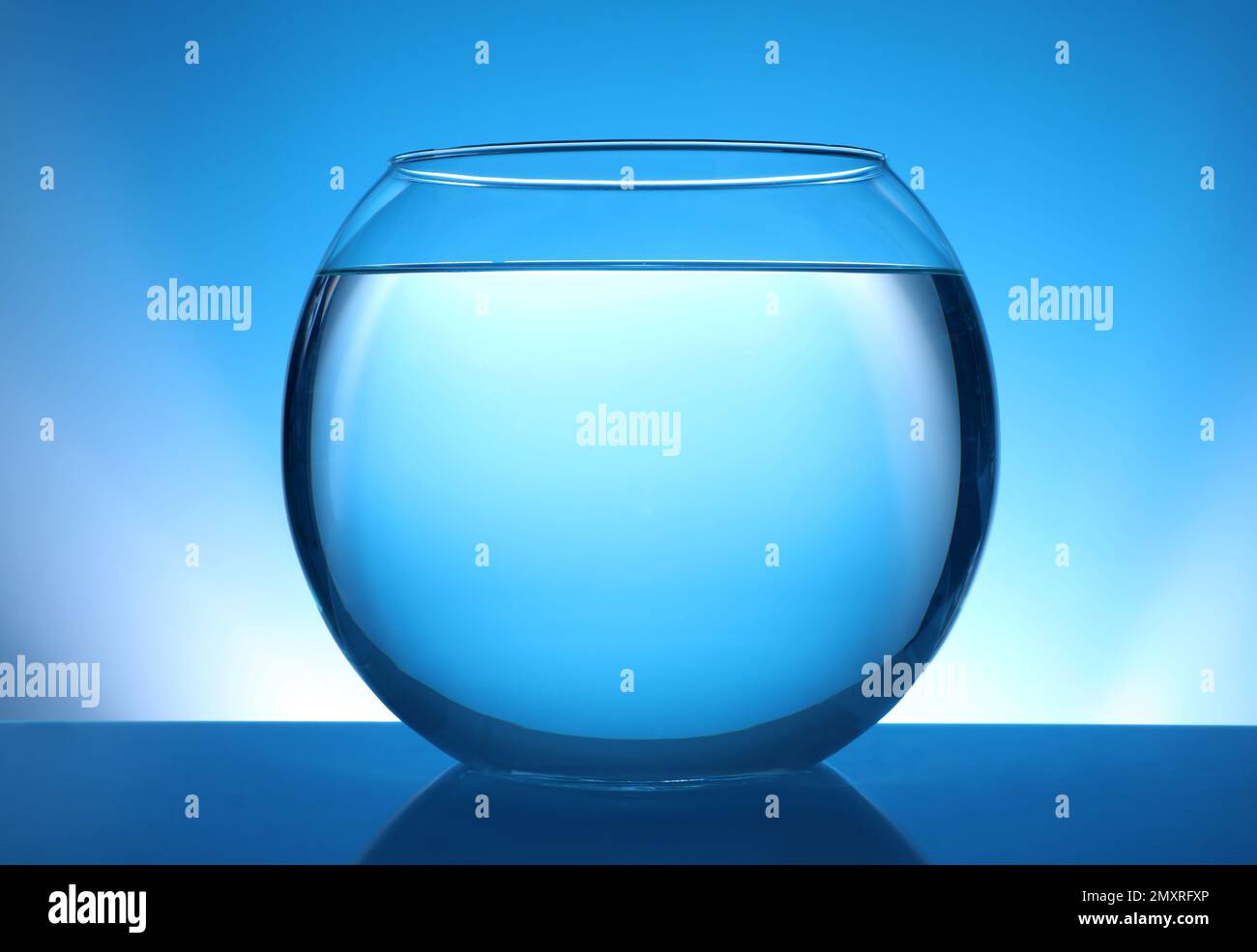 Glass fish bowl with clear water on blue background Stock Photo - Alamy