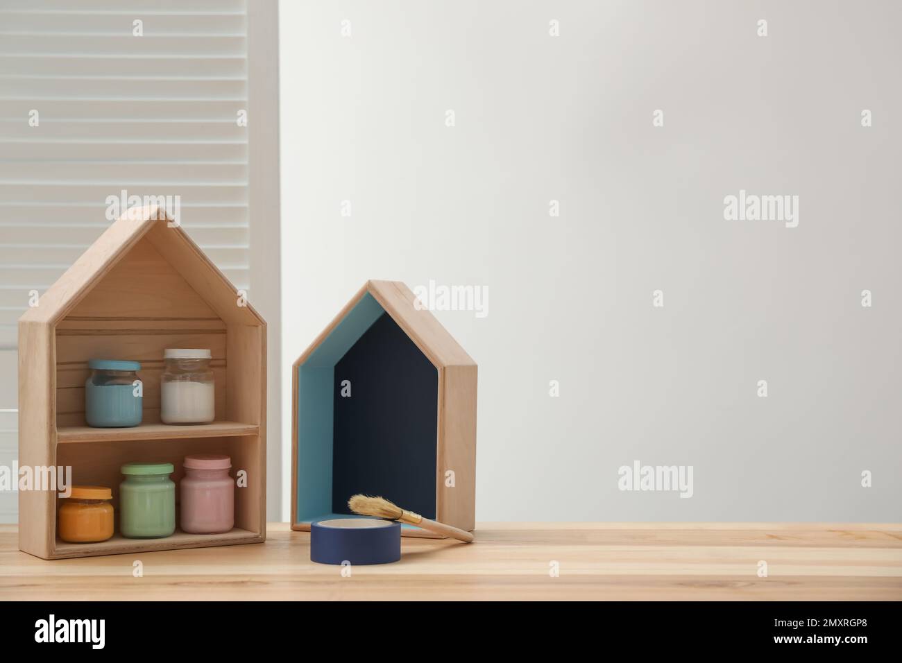 House shaped shelf brush and jars of paints on table. Space for text ...