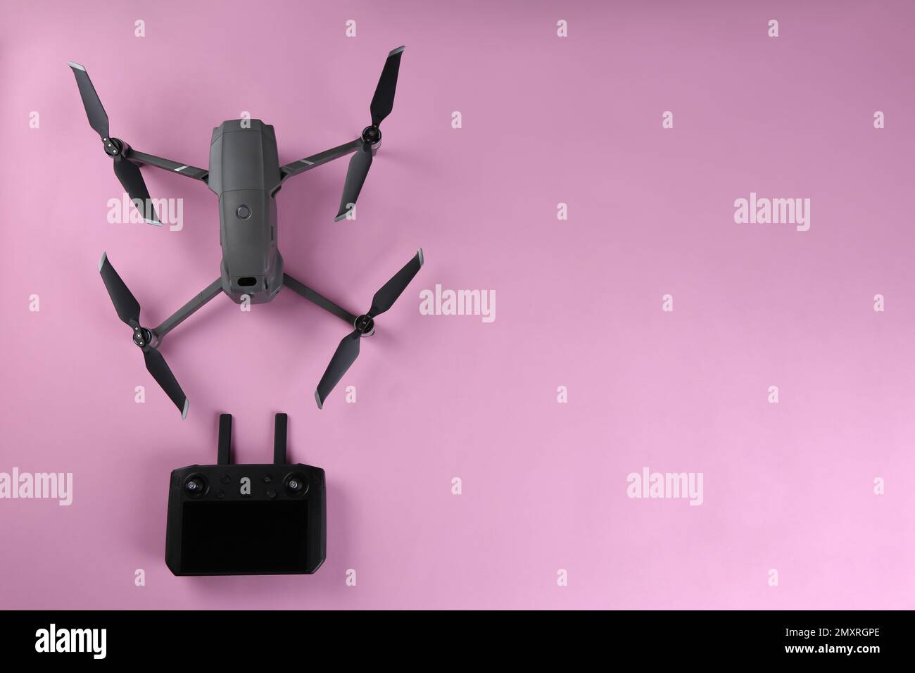 Modern drone with controller on pink background, flat lay. Space for ...