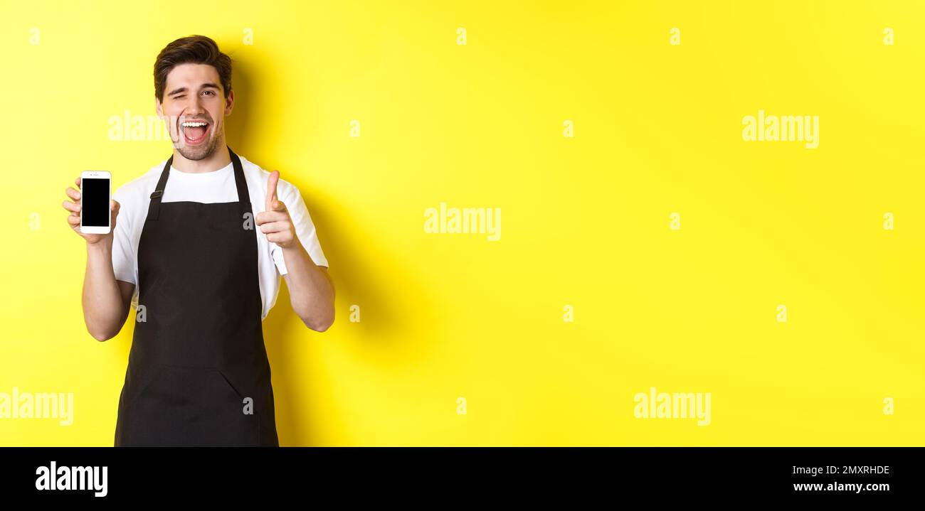 Happy waiter showing mobile screen and thumb up, recommending cafe ...