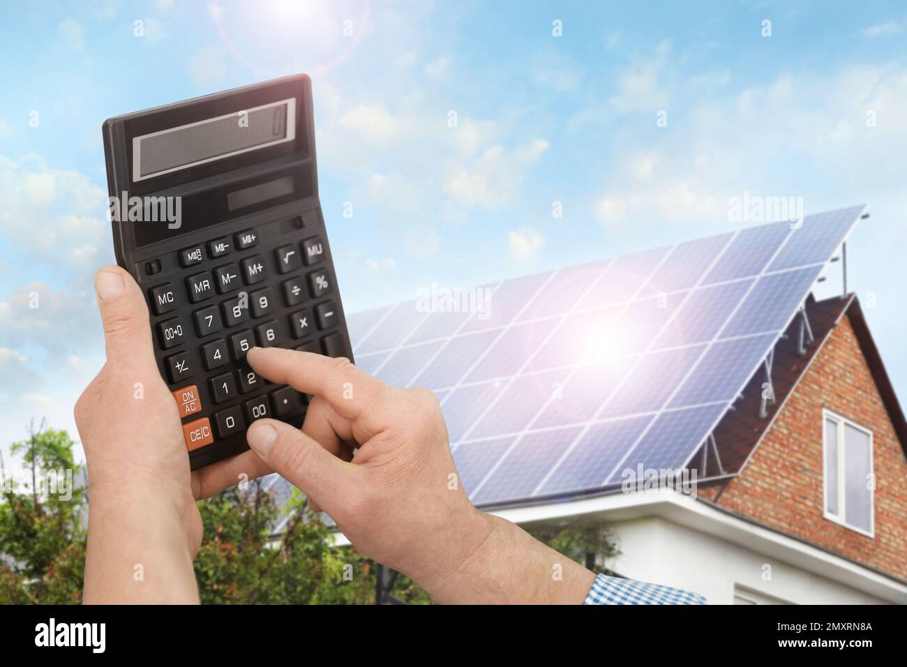 Man using calculator against house with installed solar panels ...