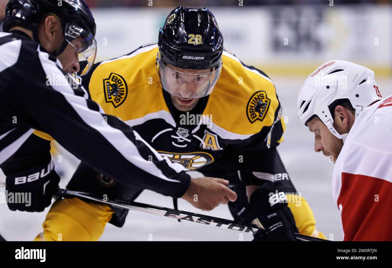 Boston Bruins center Dominic Moore, center, eyes the puck on a face-off ...