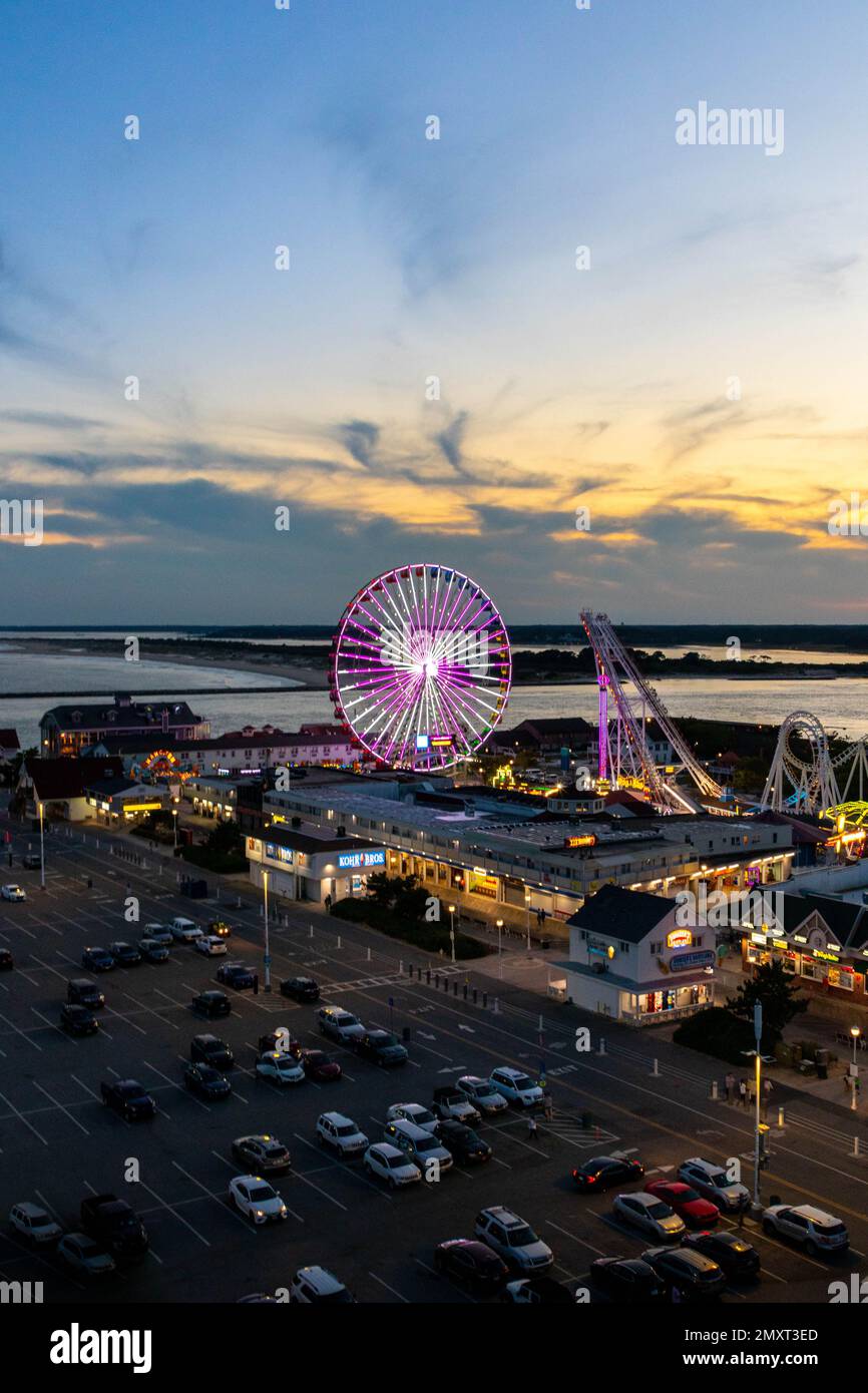 A vertical of the glowing colorful Ferris wheel at an amusement park in ...