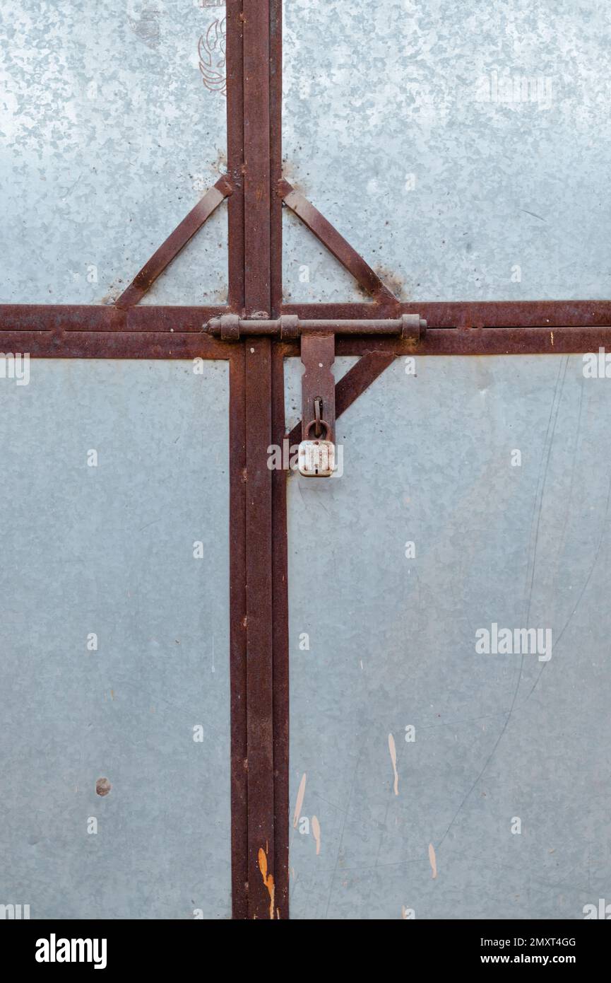 A vertical shot of a metal gate with a rusty crossbar lock Stock Photo ...