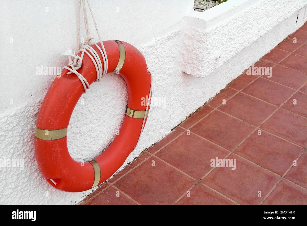 Lifebuoy hanging on a rope on a white wall Stock Photo - Alamy