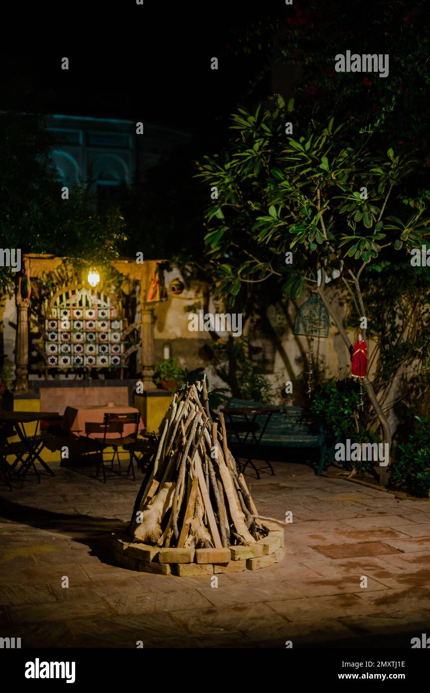 A view of big unlit campfire in the backyard of the house with tables ...