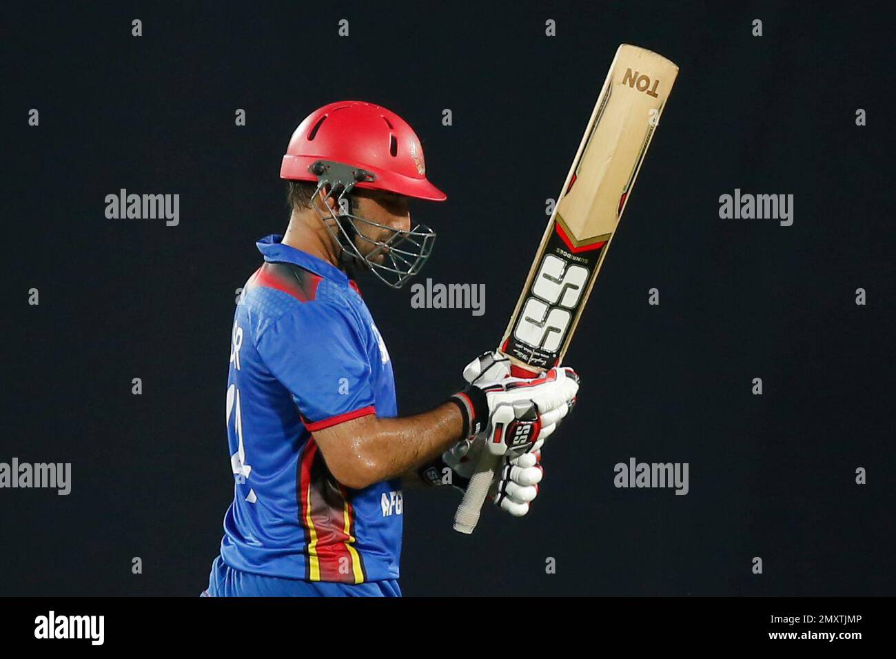 Afghanistan's captain Asghar Stanikzai watches his bat as he walks back ...