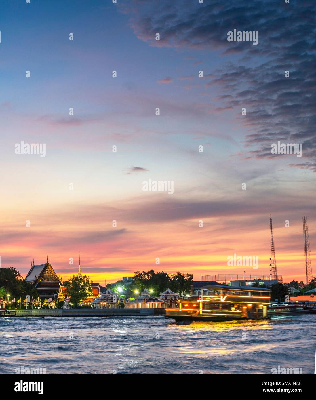 At dusk,a pleasure boat,colorfully illuminated by strip lights, drifts ...