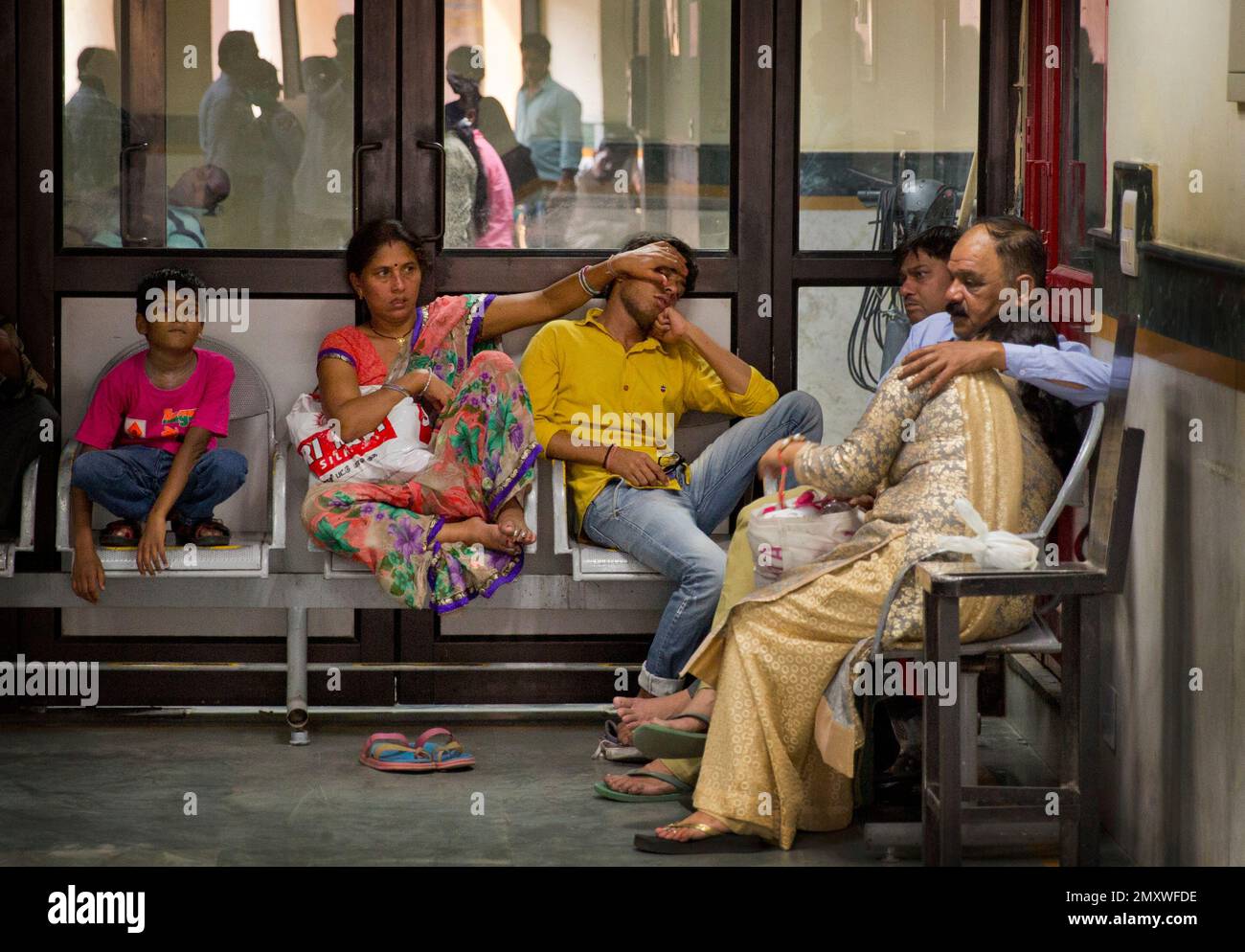 People suffering from high fever sit with their relatives to see a ...