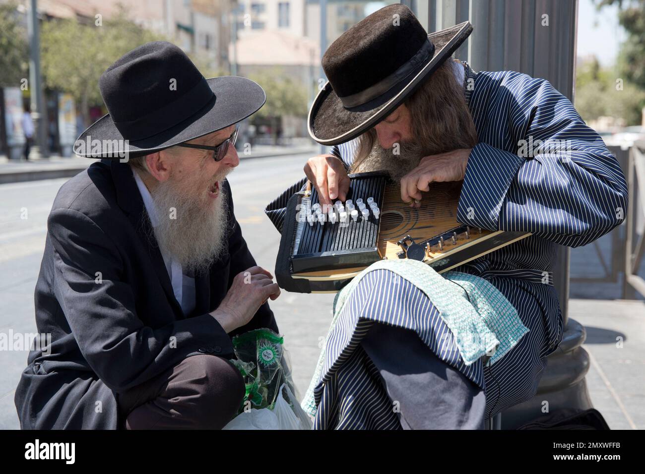 An ultra-Orthodox Jewish man plays music as another sings on a street ...