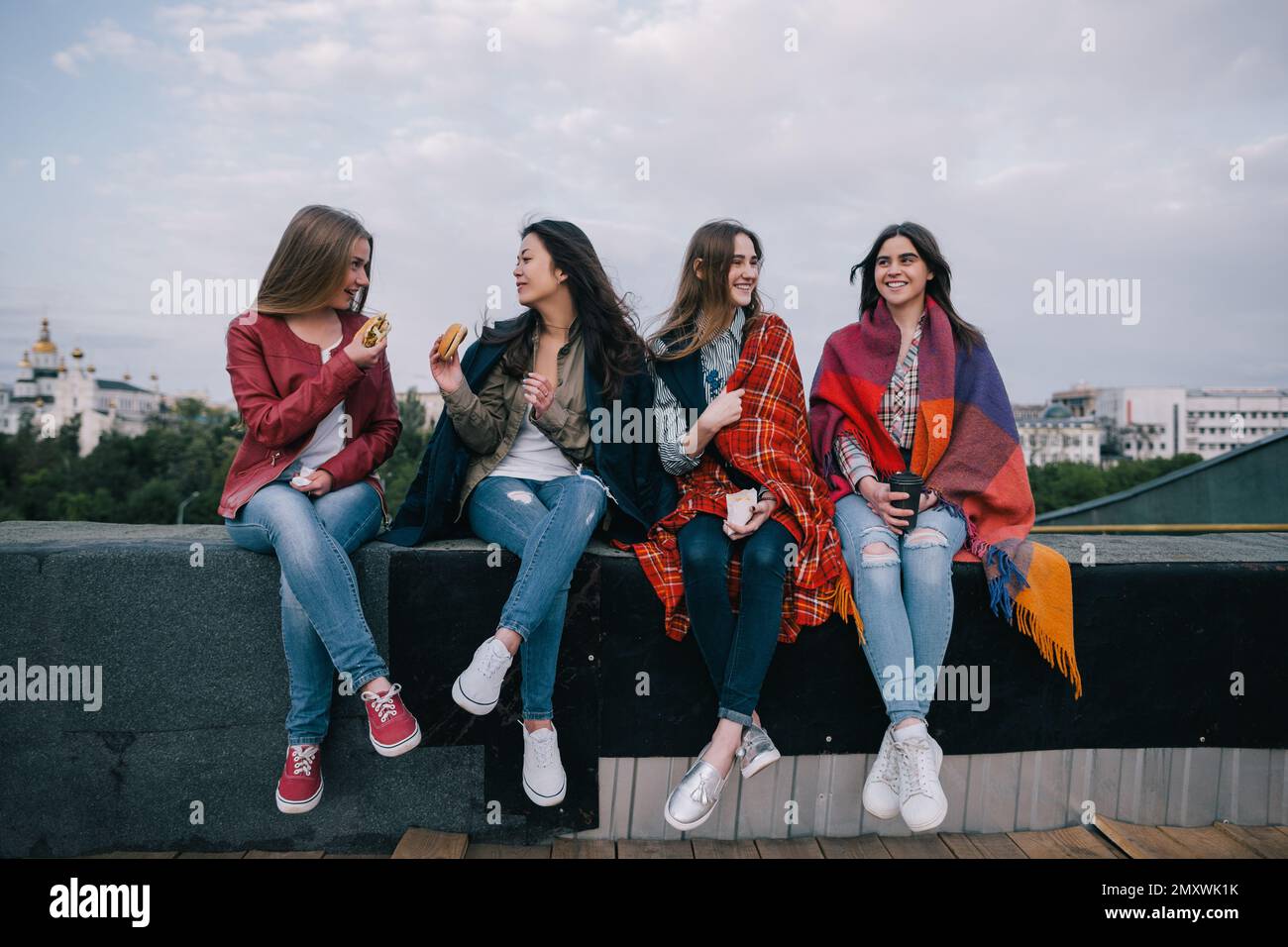 Joyful young girls spending good time together on roof. Close friends ...