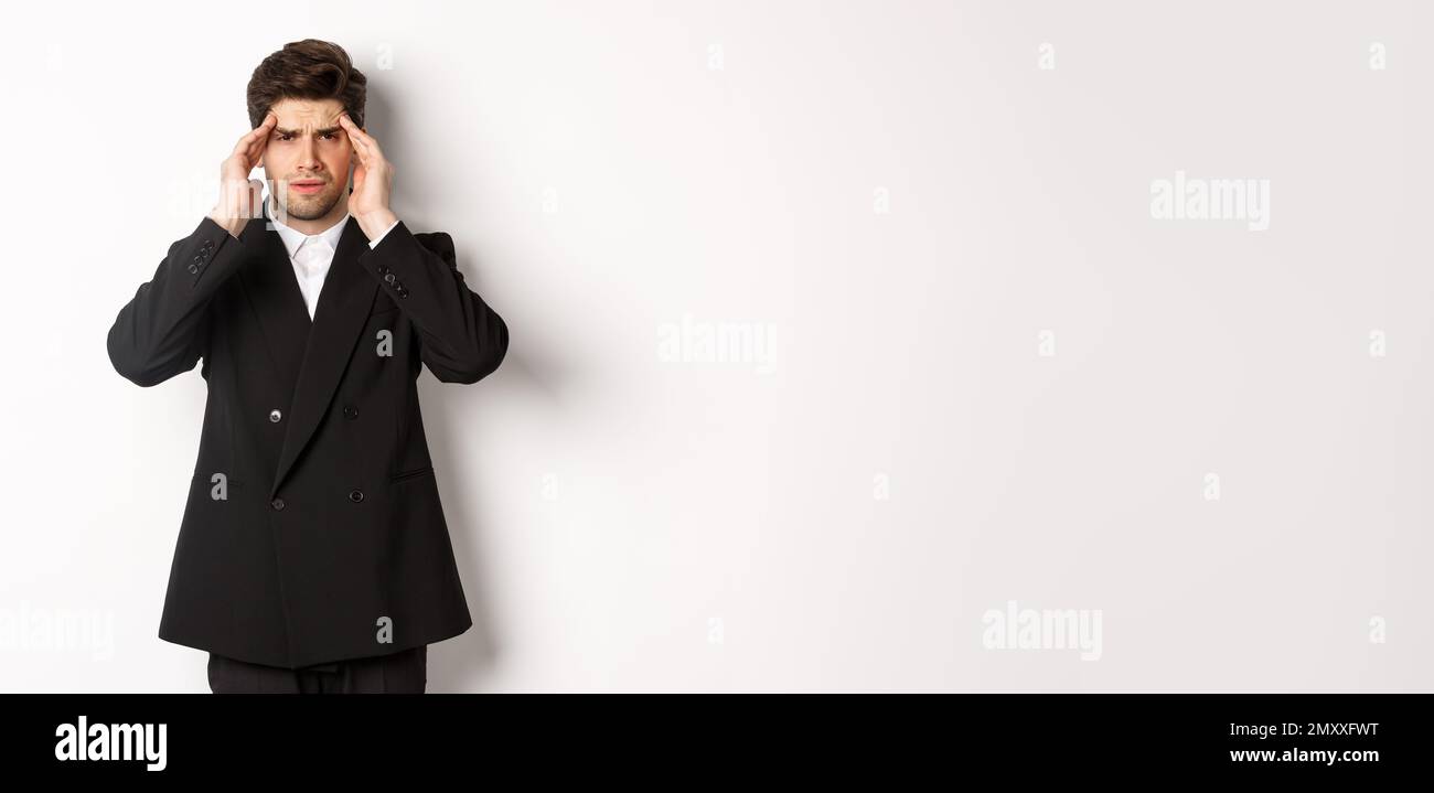 Image of businessman in black suit, touching head and looking dizzy ...