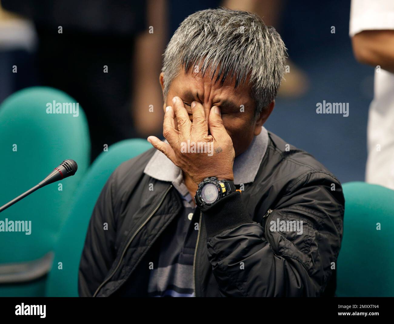 Former Filipino militiaman Edgar Matobato pinches his nose during a ...