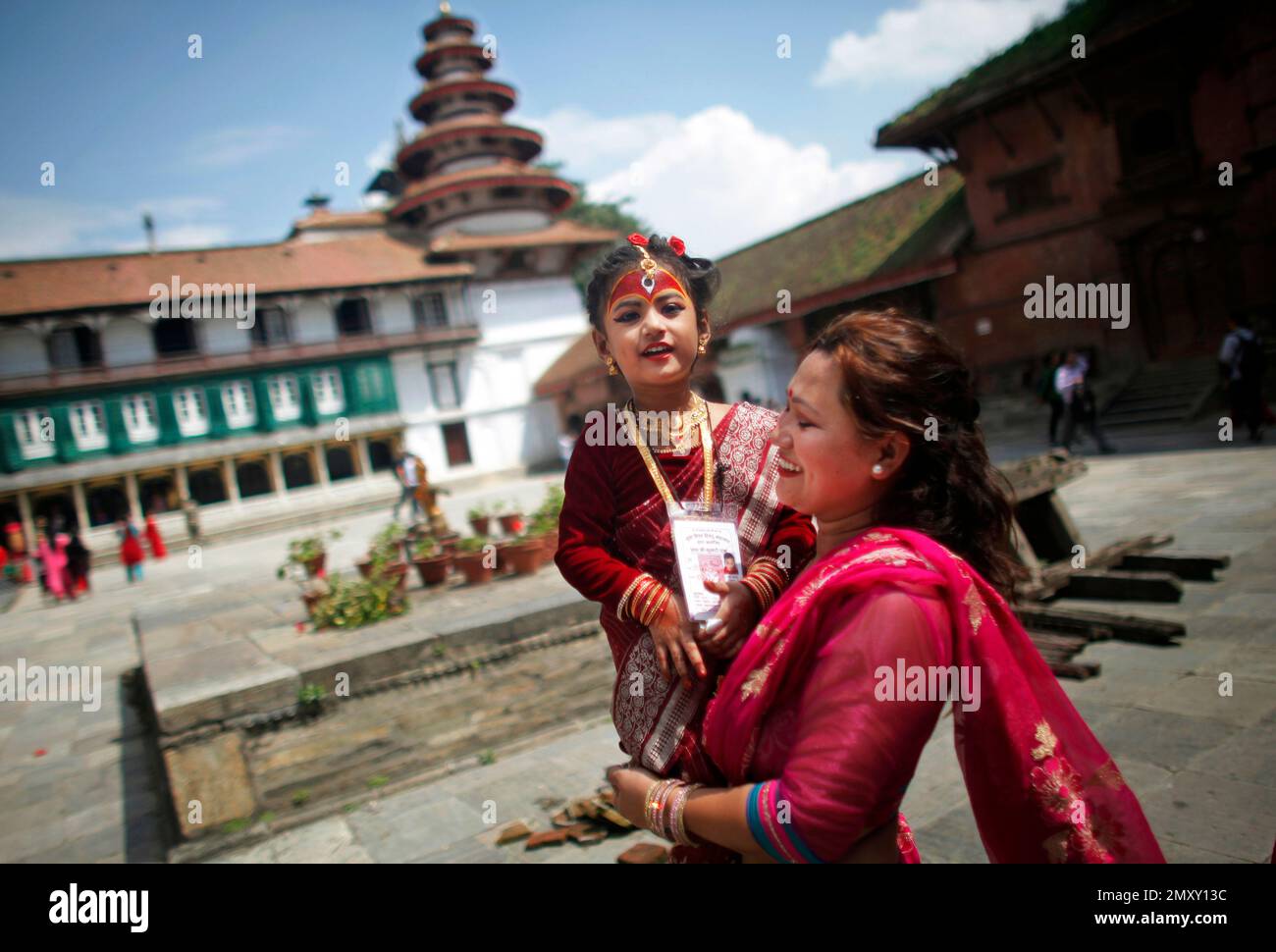 A young Nepalese girl wearing traditional costume is carried by her ...