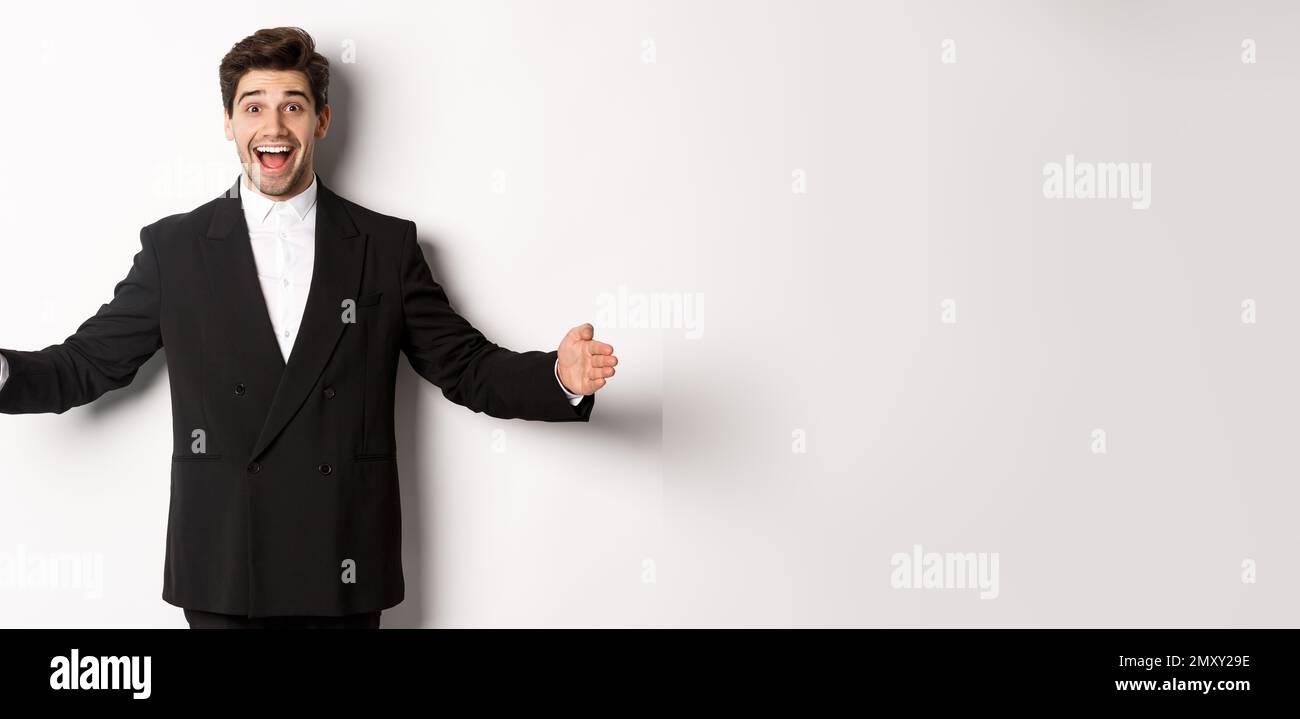 Portrait of excited handsome man in suit, shaping big object on copy ...