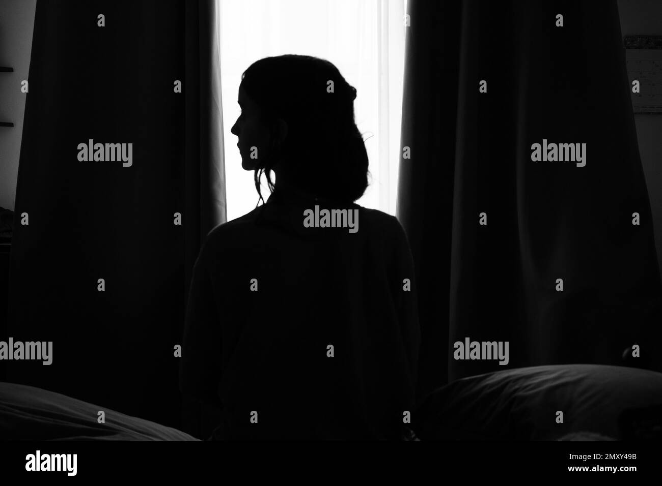 A silhouette of female sitting on bed dark room Stock Photo - Alamy