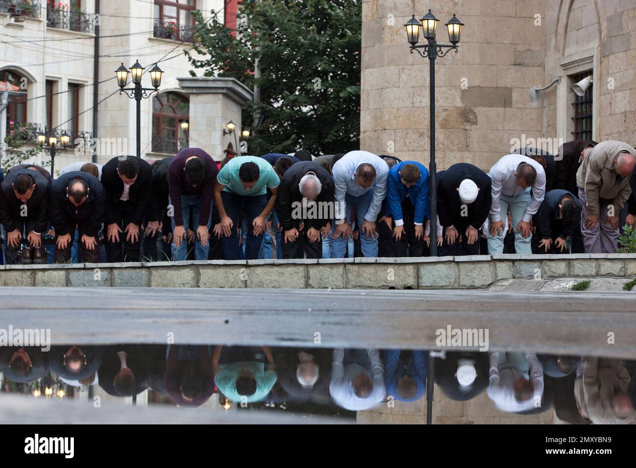 Kosovars are reflected in water during Eid al-Adha prayers outside Sultan Mehmet Fatih mosque in ...