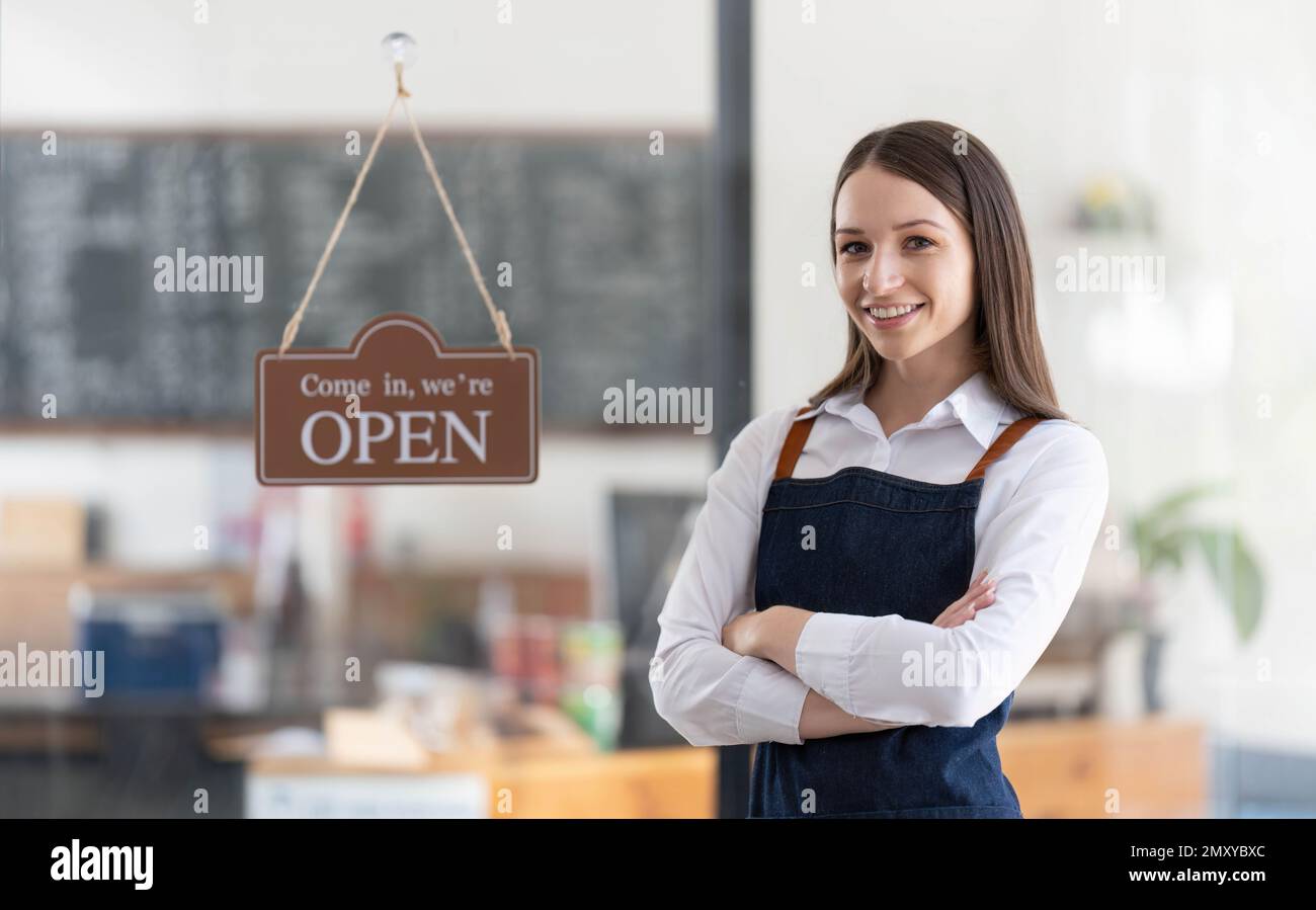 Happy business woman is a waitress in an apron, the owner of the cafe ...