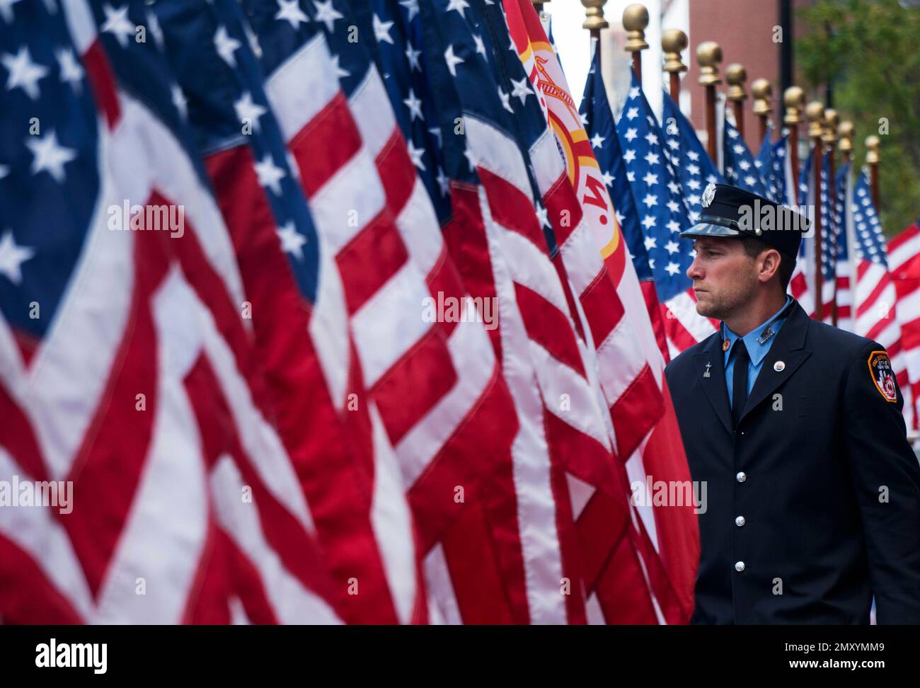 An FDNY firefighter walks among flags at the FDNY Memorial Wall on ...