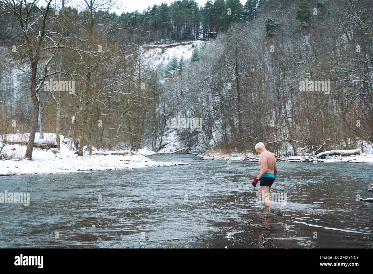 Man walking and going to swim in the cold water of a river in a forest ...