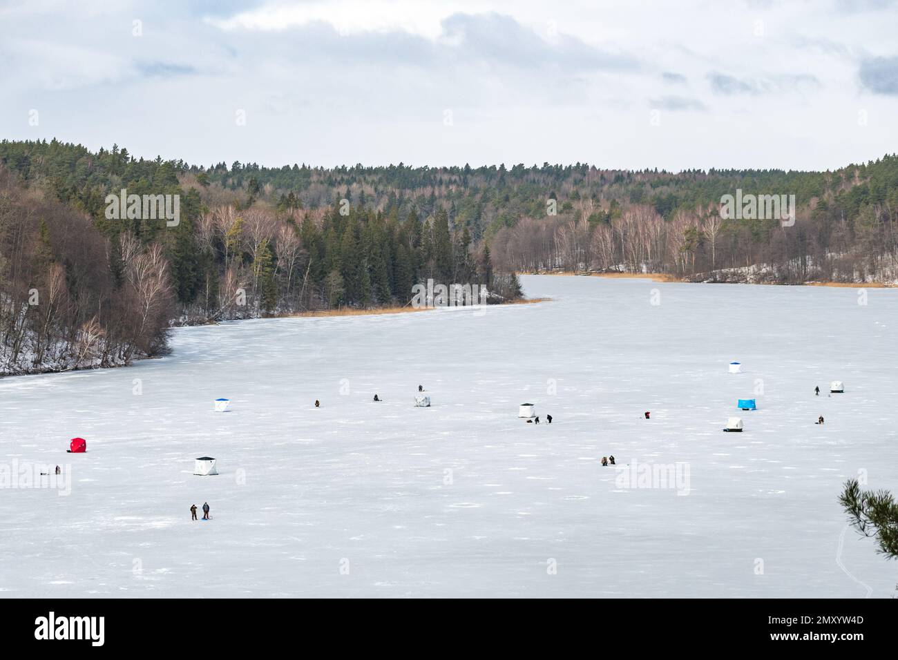 Fishermen fishing on a frozen lake in winter with fishing pole or rod ...