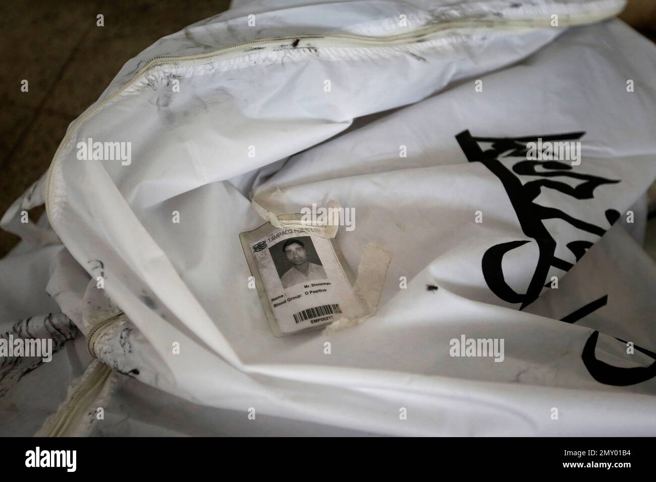 An identity card is placed on the body of a fire victim at a makeshift ...