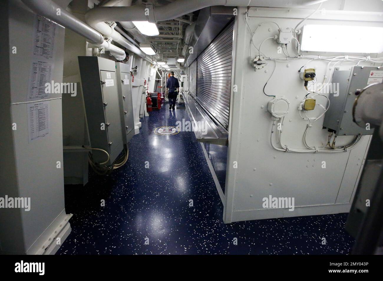 A sailor walks in a passageway aboard the USS Zumwalt while at dock at ...