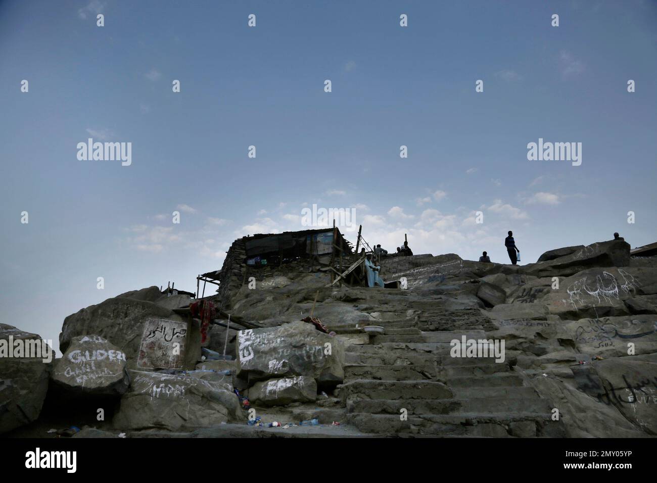 Men sit on steps of Noor Mountain, where Prophet Muhammad received his ...
