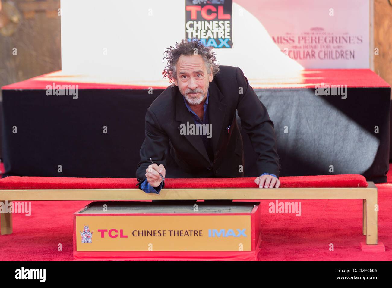 Tim Burton signs his name in wet cement at his hand and footprint ...