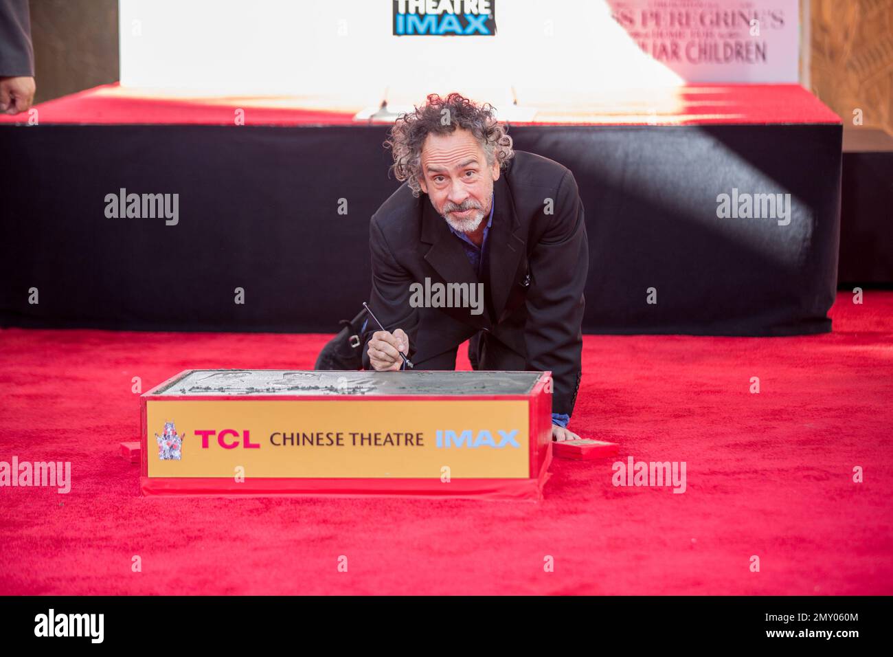 Tim Burton signs his name in wet cement at his hand and footprint ...