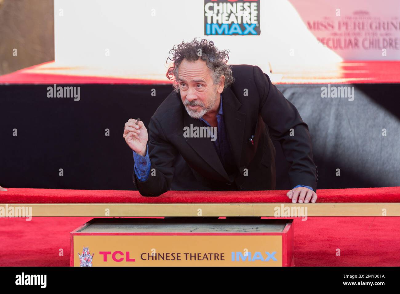 Tim Burton signs his name in wet cement at his hand and footprint ...