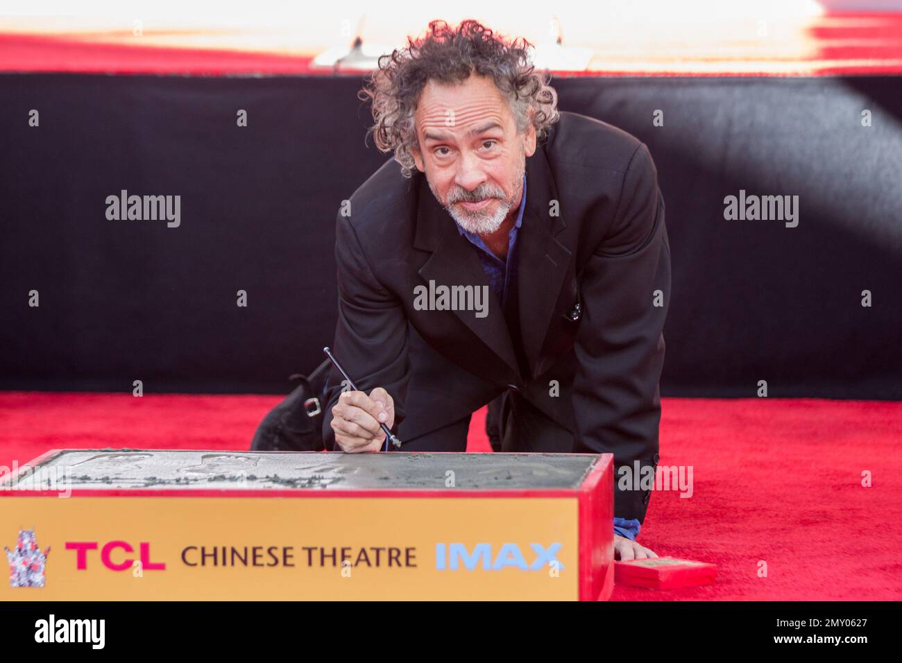 Tim Burton signs his name in wet cement at his hand and footprint ...