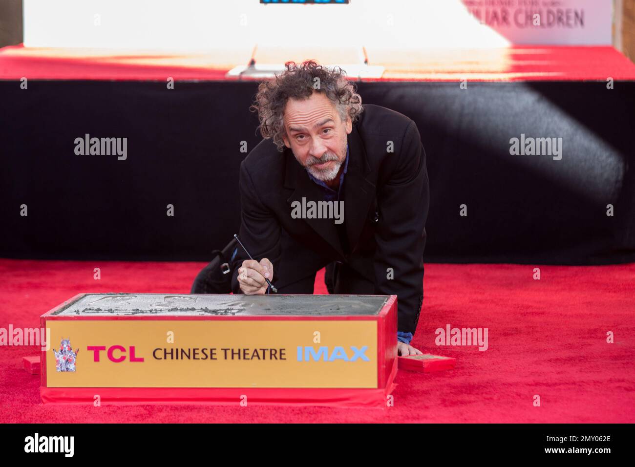 Tim Burton signs his name in wet cement at his hand and footprint ...