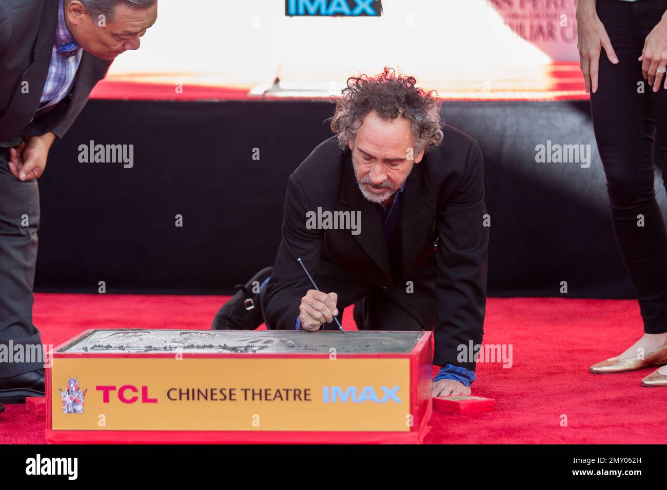 Tim Burton signs his name in wet cement at his hand and footprint ...