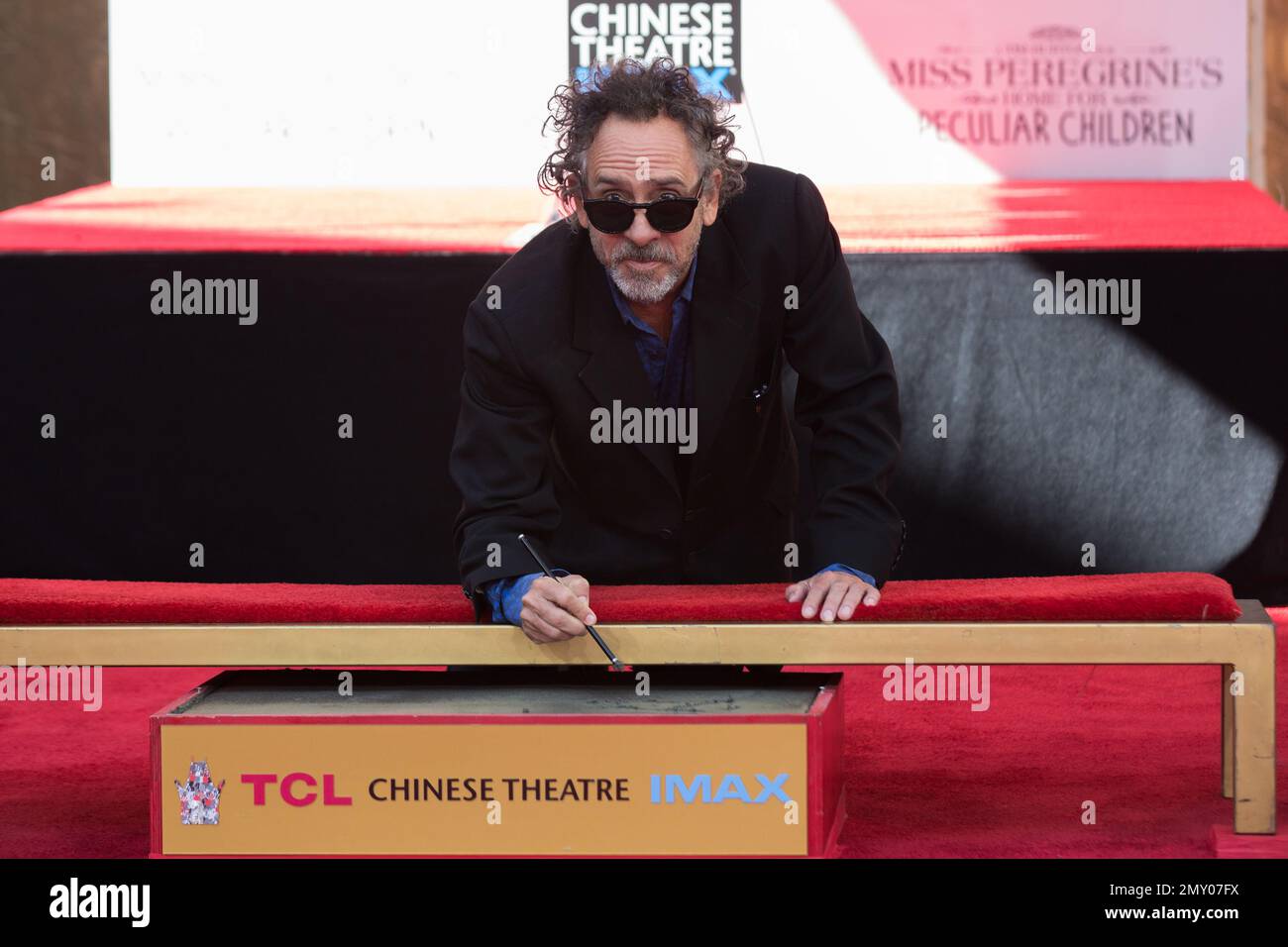 Tim Burton signs his name in wet cement at his hand and footprint ...
