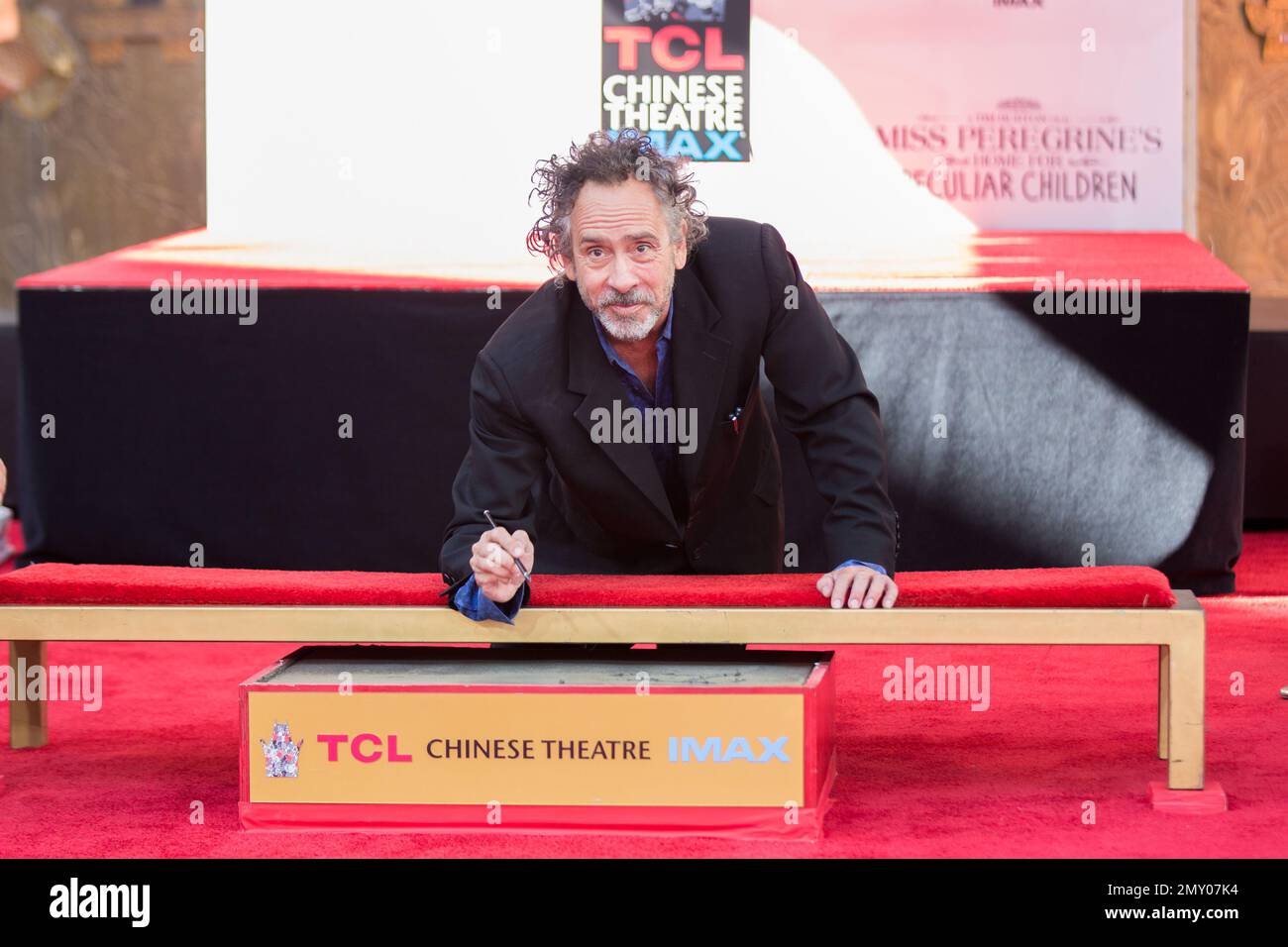 Tim Burton signs his name in wet cement at his hand and footprint ...