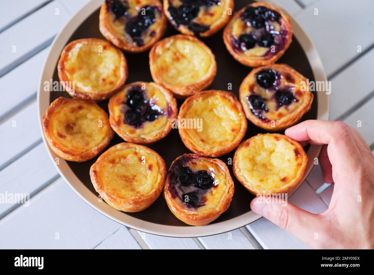 Hand taking Pasteis de Belem, Portuguese pastel de Nata Custard Tarts ...