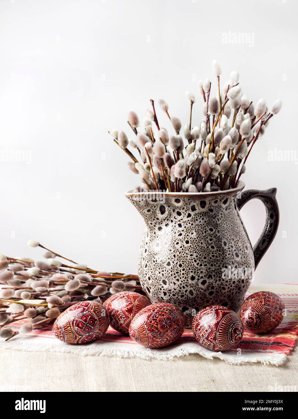Easter still life with Pysanka and willow branches in ceramic jug on ...