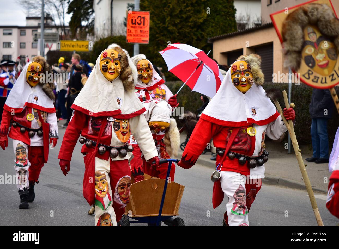 A group of masked people garbed in red and white jester attire parading ...