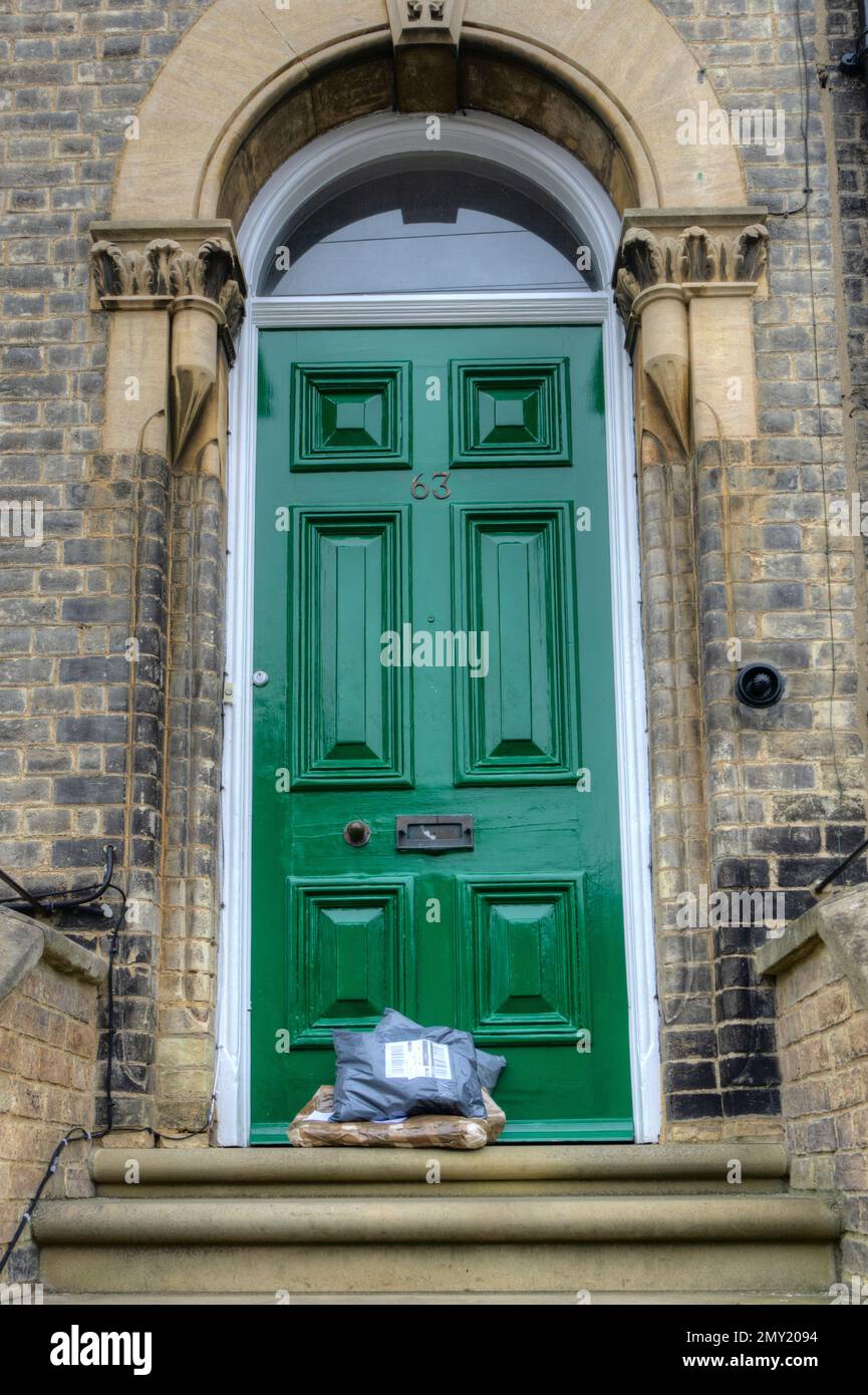 Parcel delivery on doorstep of brick built home with green door ...