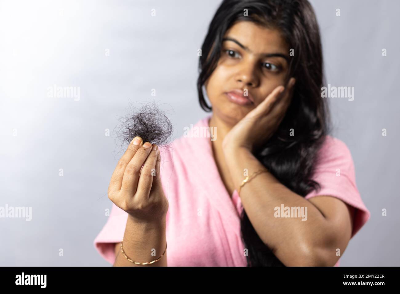 Selective focus on fallen hair held in hand by a worried Indian woman ...
