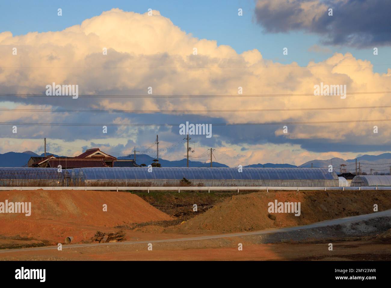 Mounds of earth by ramp to construction site under billowing clouds ...