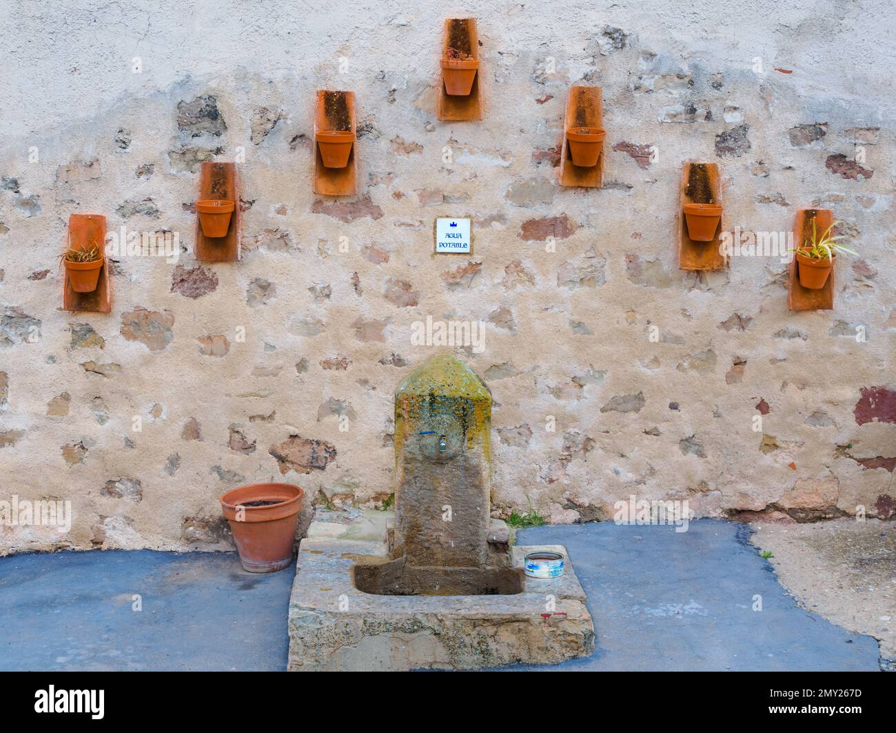 Fountain with rustic wall in the background with 7 red pots distributed ...