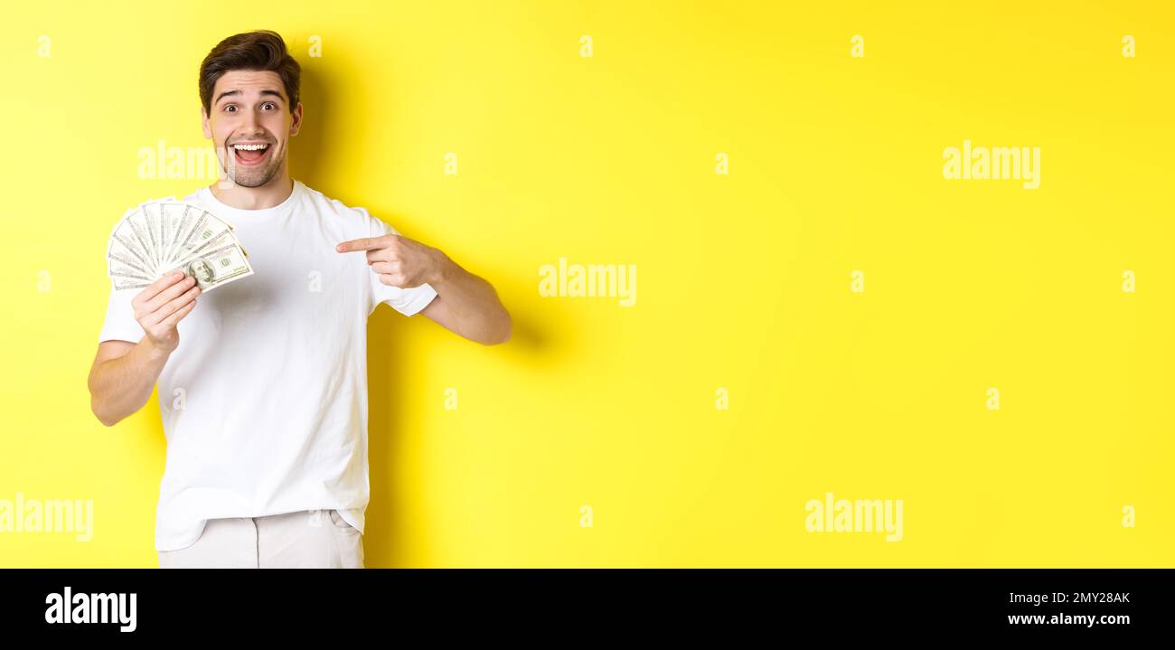 Happy handsome guy pointing finger at money, concept of credit and loan ...